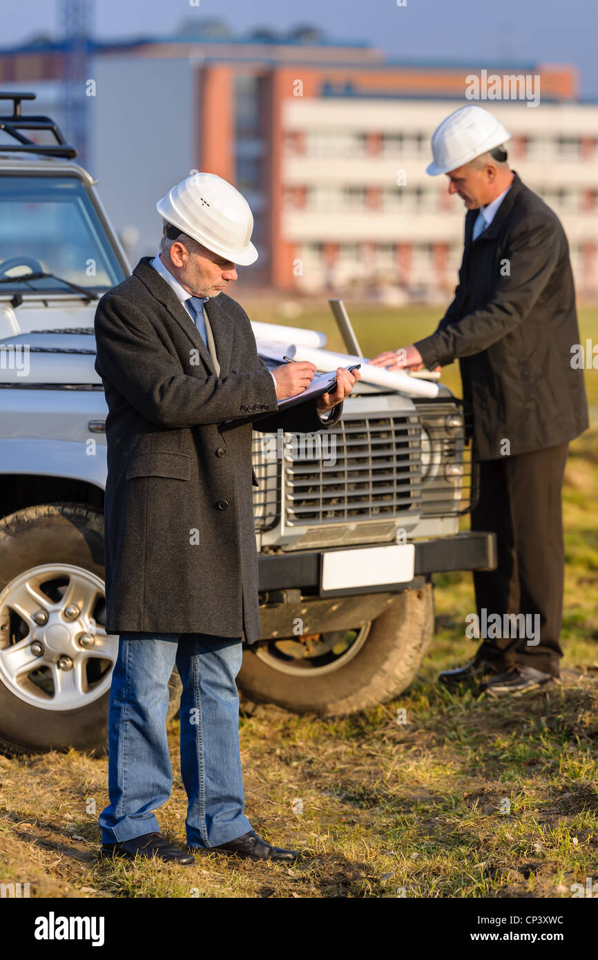 Male architect developers on construction site making notes building ...