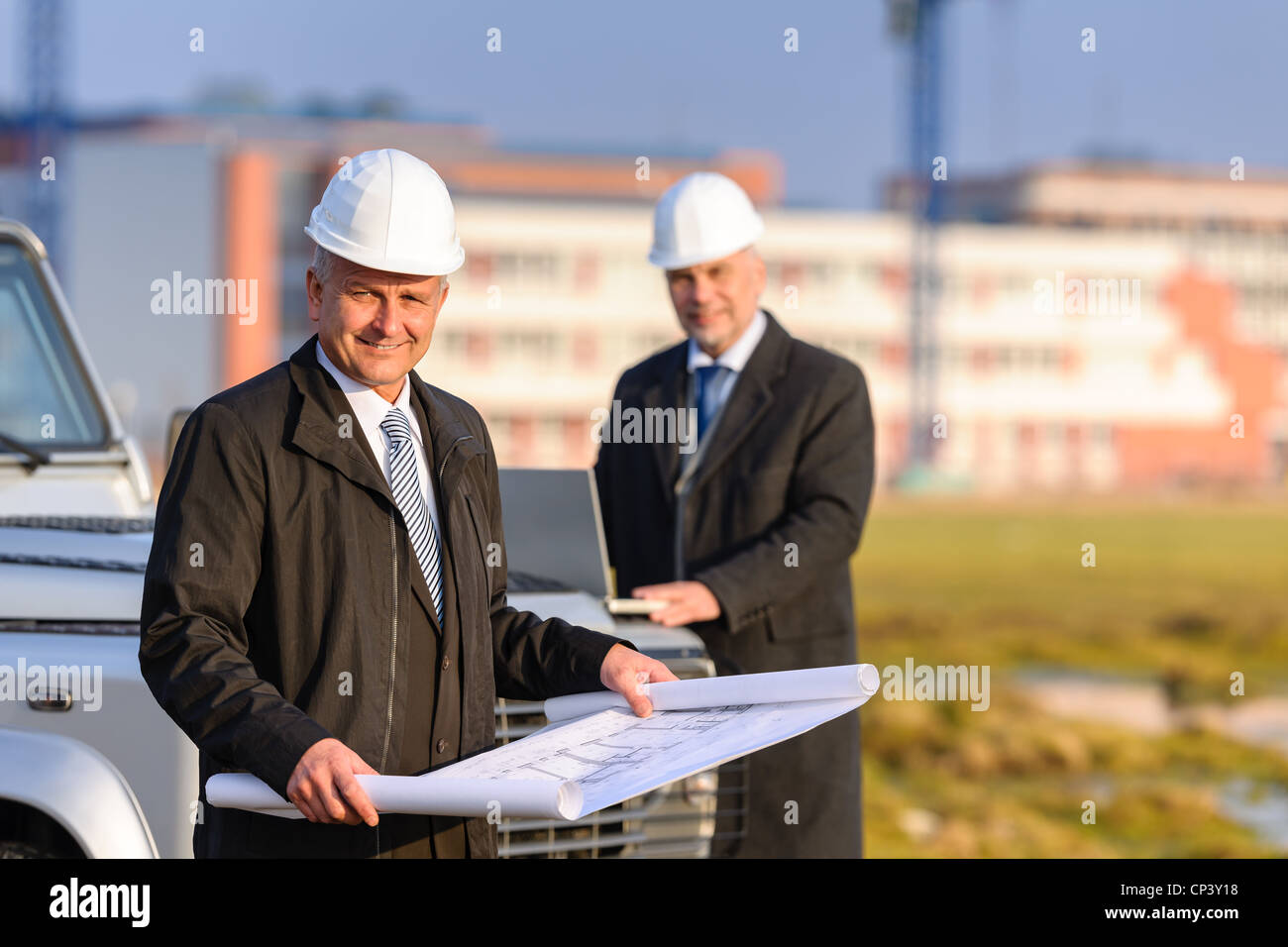 Two architect developers reviewing building plans at construction site ...