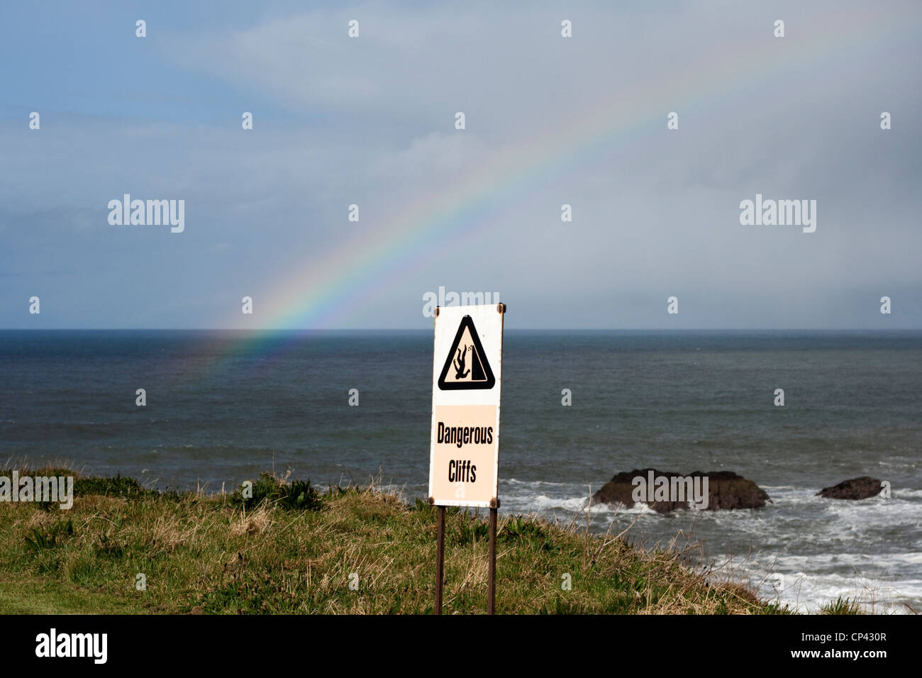 Dangerous cliffs warning sign with rainbow Stock Photo - Alamy