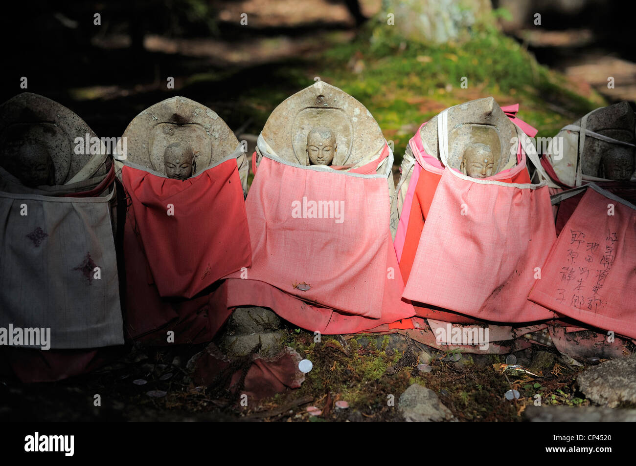 row of small decorated stone figures in sunlight at Okunoin cemetery ...