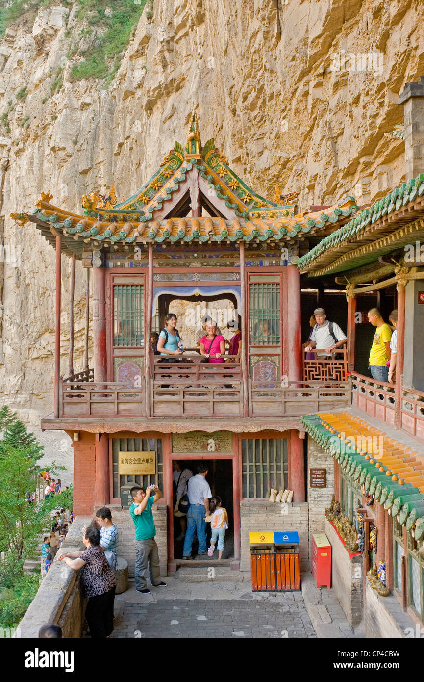 Tourists pose for the camera at The Hanging Temple or Hanging Monastery ...
