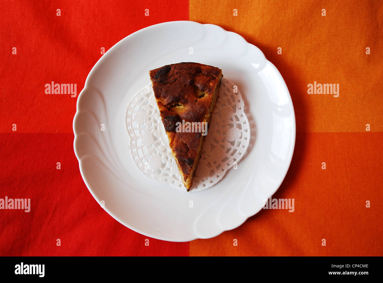 Slice of an apple pie on white china dish and orange background, aerial ...