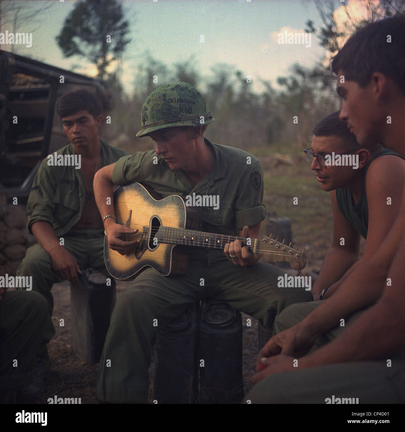 Vietnam War. US Army infantrymen gather around a guitar player and sing ...