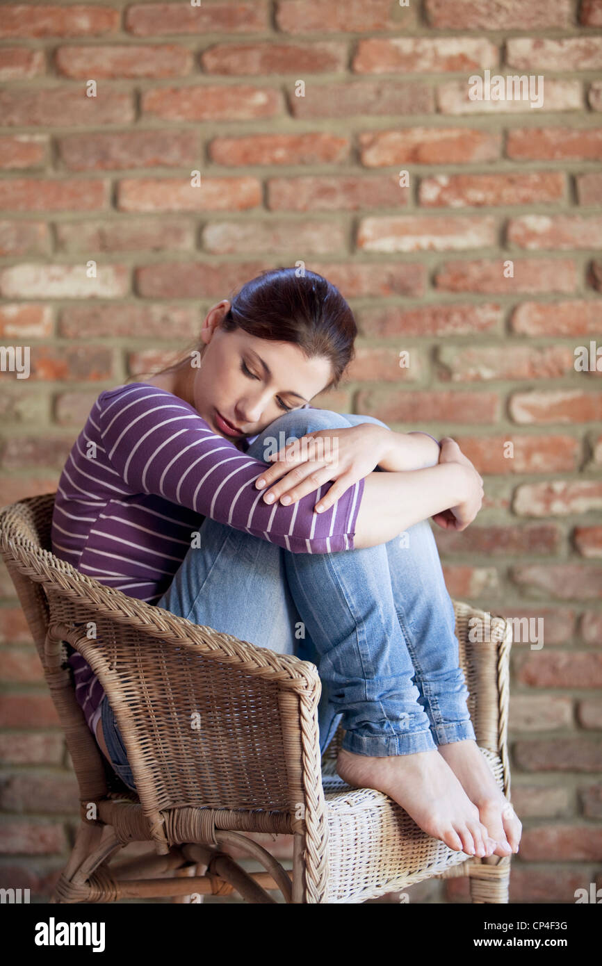 a sad woman sitting on a wicker chair Stock Photo - Alamy