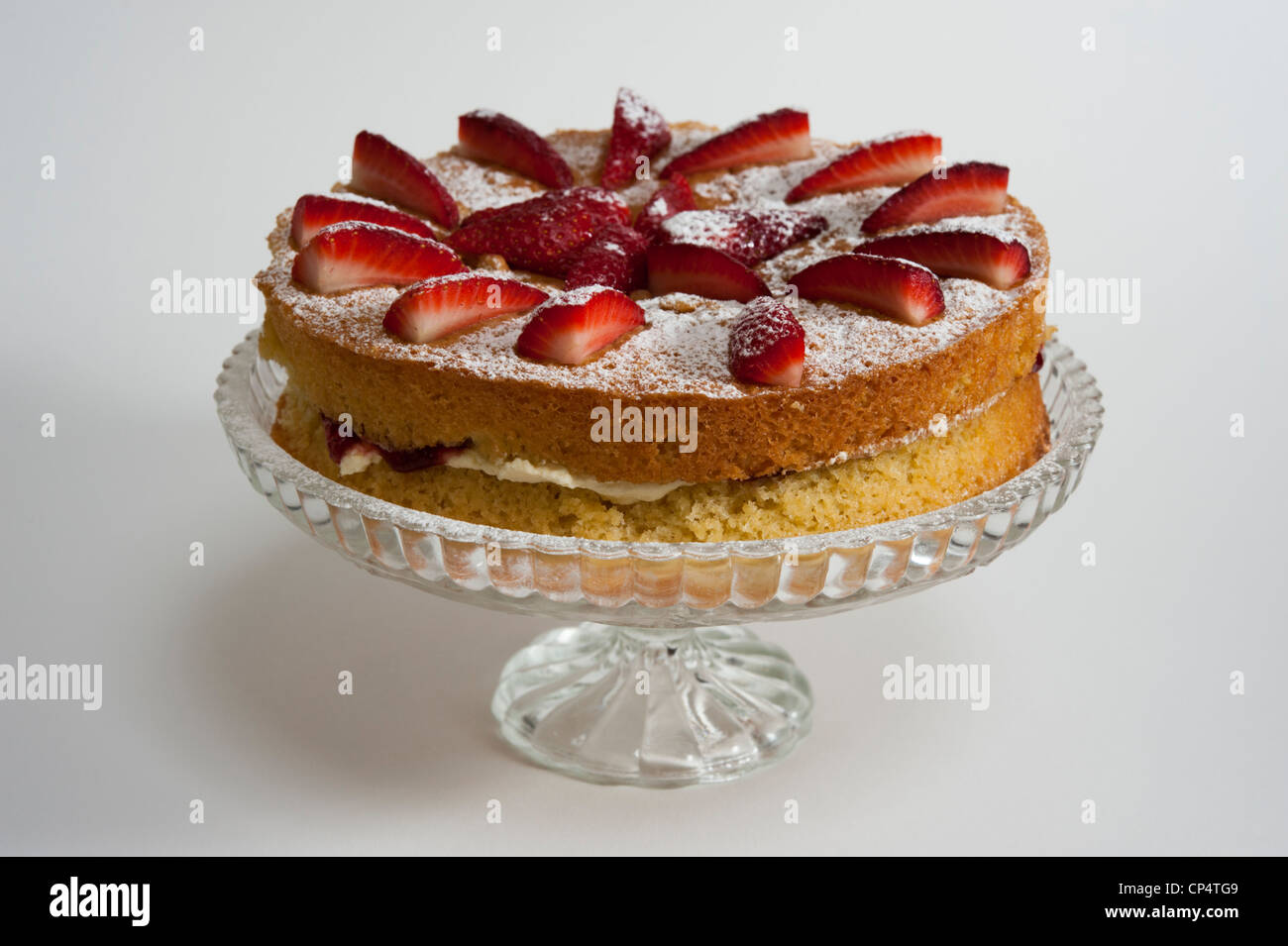 A victoria sponge cake with strawberries and icing sugar on top ...