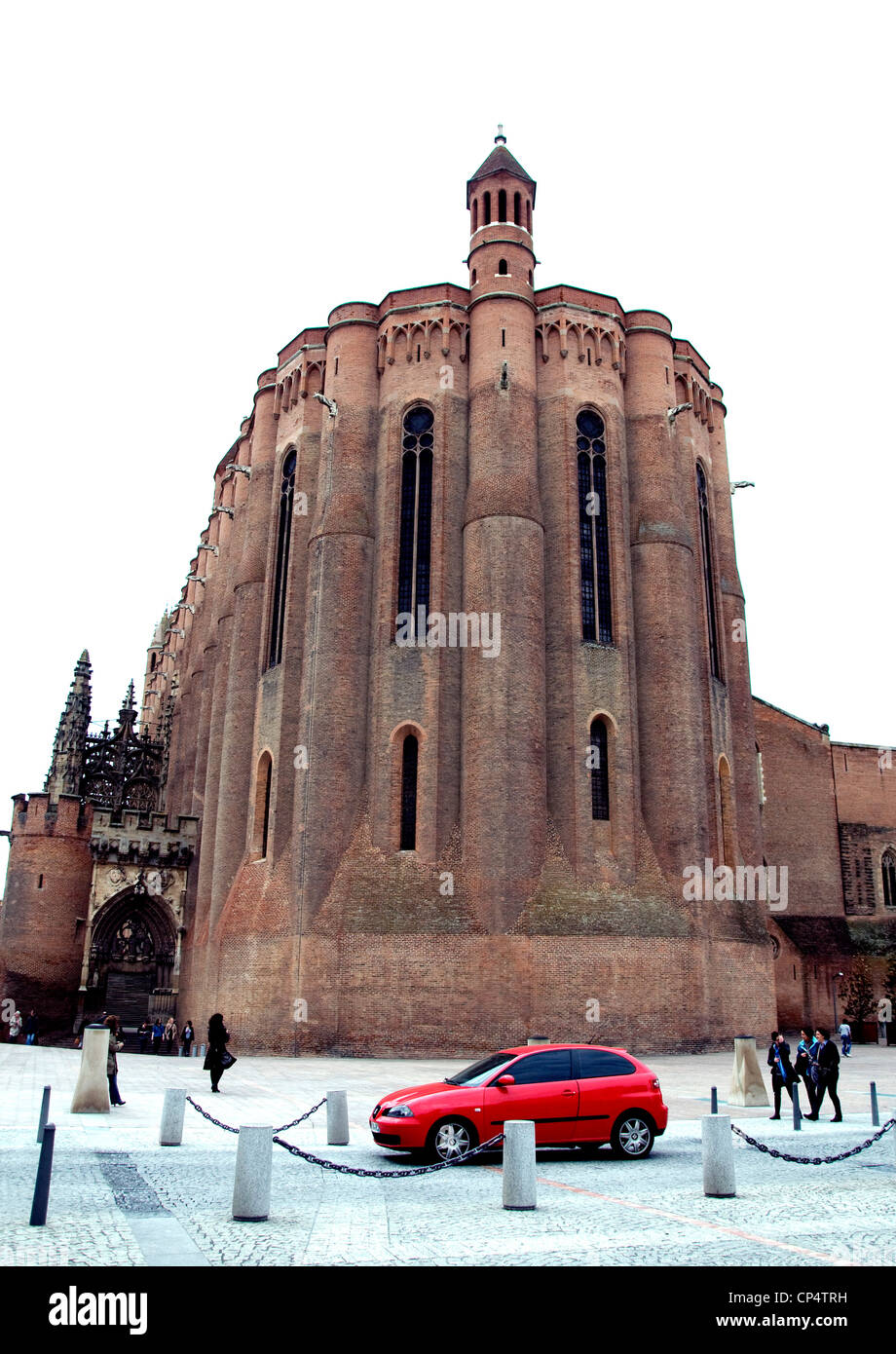 In medieval Albi, France, a small red car drives behind the city's vast ...