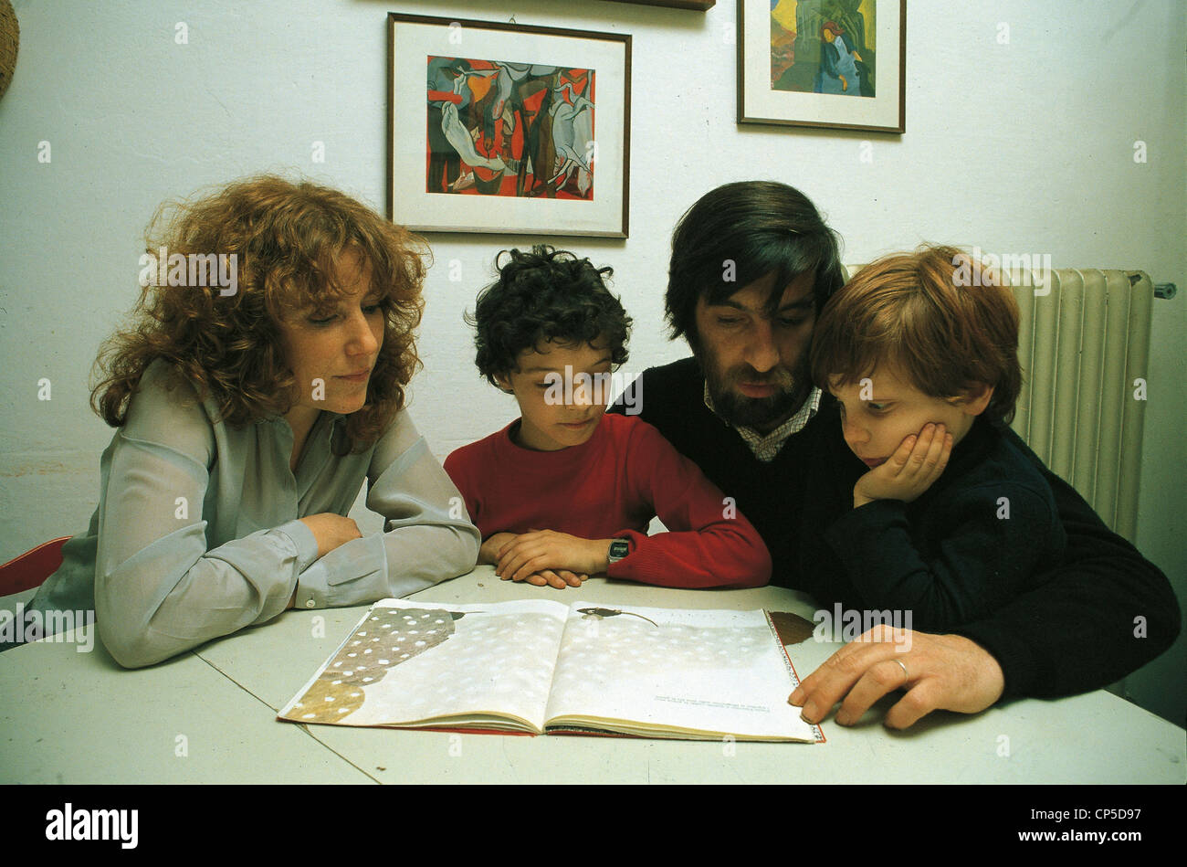 People: Family sitting at a table reading a book Stock Photo - Alamy