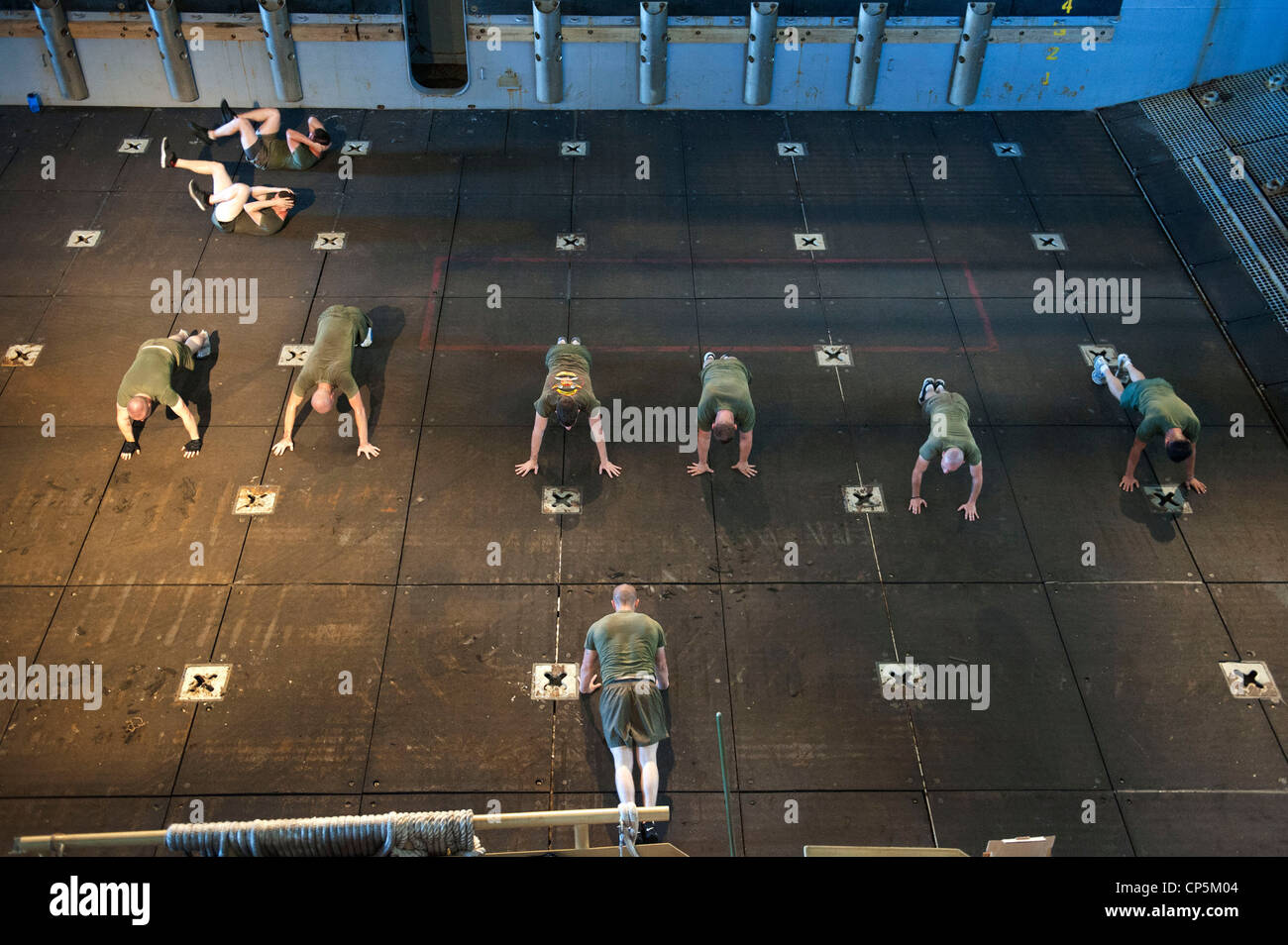 Marines hold group physical training in the well deck of the amphibious ...