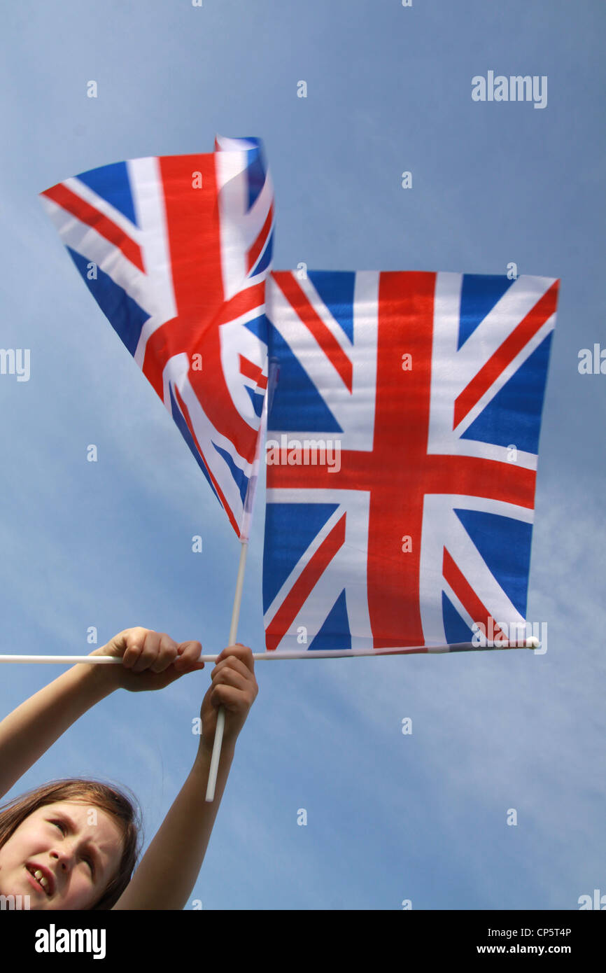 female child holding Jubilee United kingdom flags blowing in wind with ...