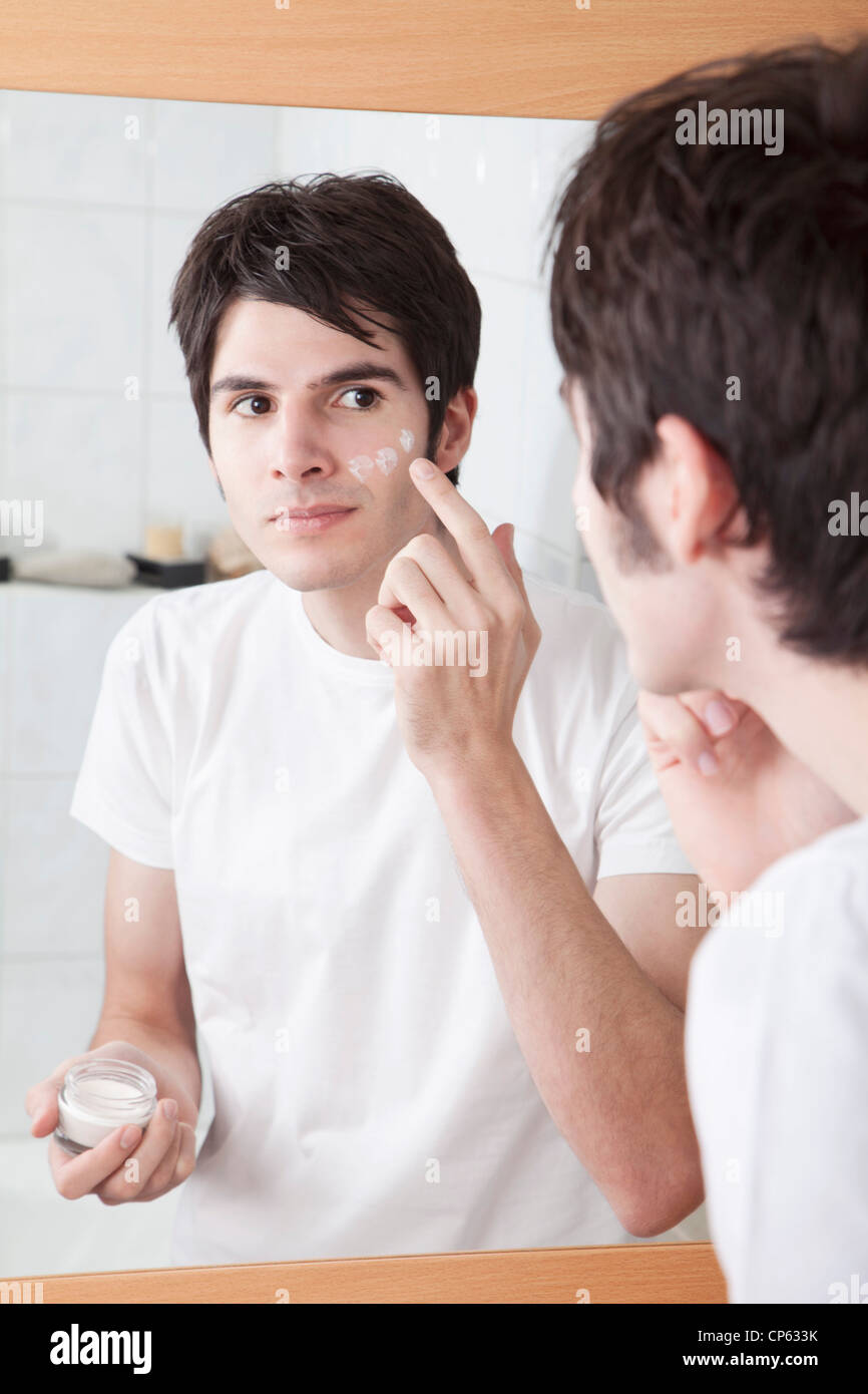 Young man applying cream on his face Stock Photo - Alamy