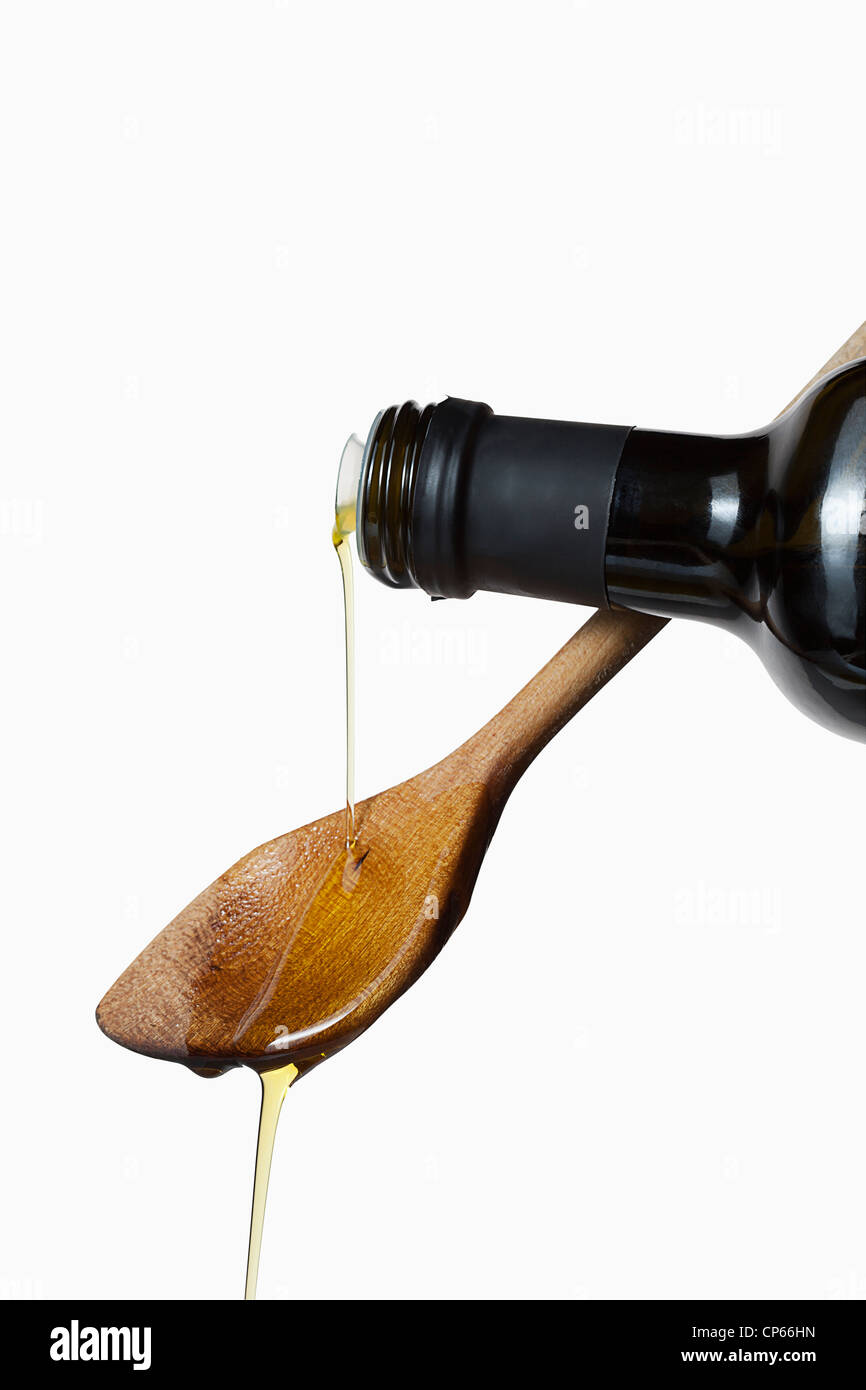 Olive oil flowing on spoon from bottle, close up Stock Photo - Alamy