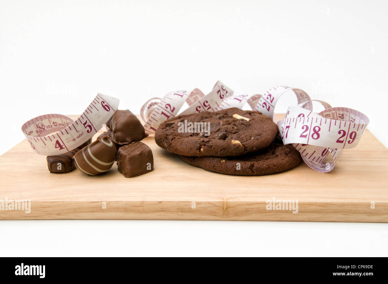 Cookies and chocolates on chopping board with measure depicting concept ...