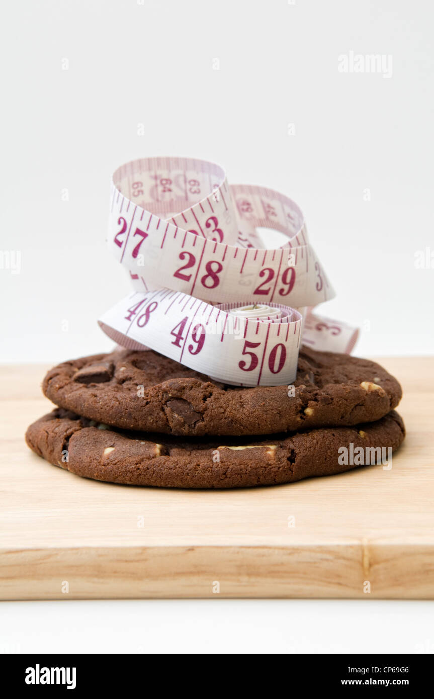 Cookies on chopping board with tape measure depicting concept that ...