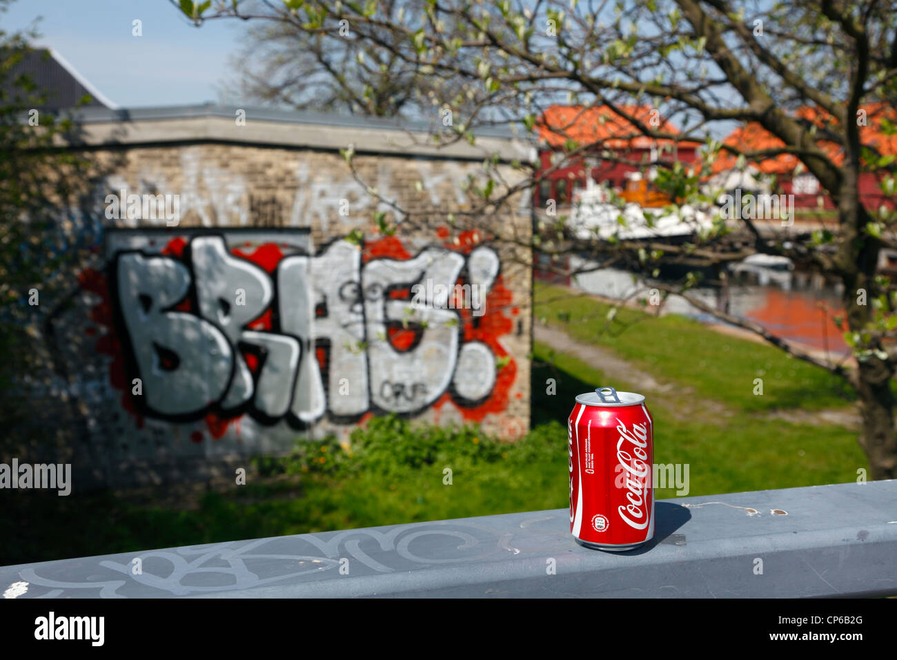 Red Coca Cola can standing on a grey handrail in background a canal ...