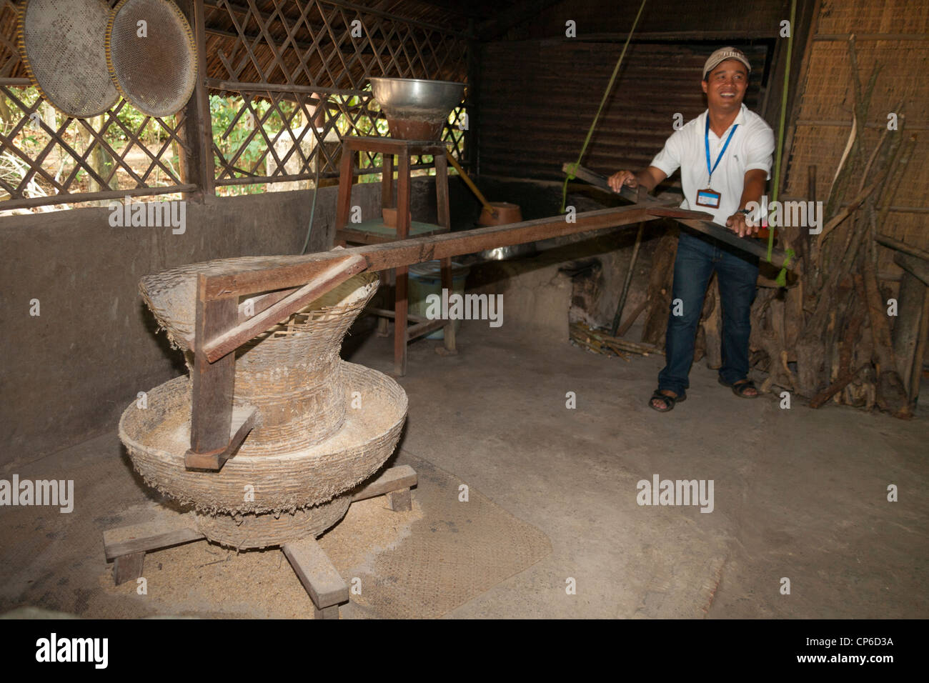 Man using a primitive machine to remove husks from rice, Ben Dinh, Cu ...