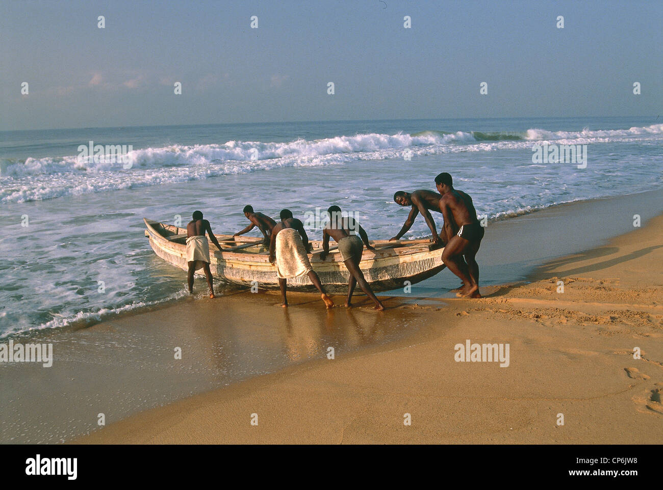 Togo - Maritime Region. A group of fishermen while pushing a boat in ...