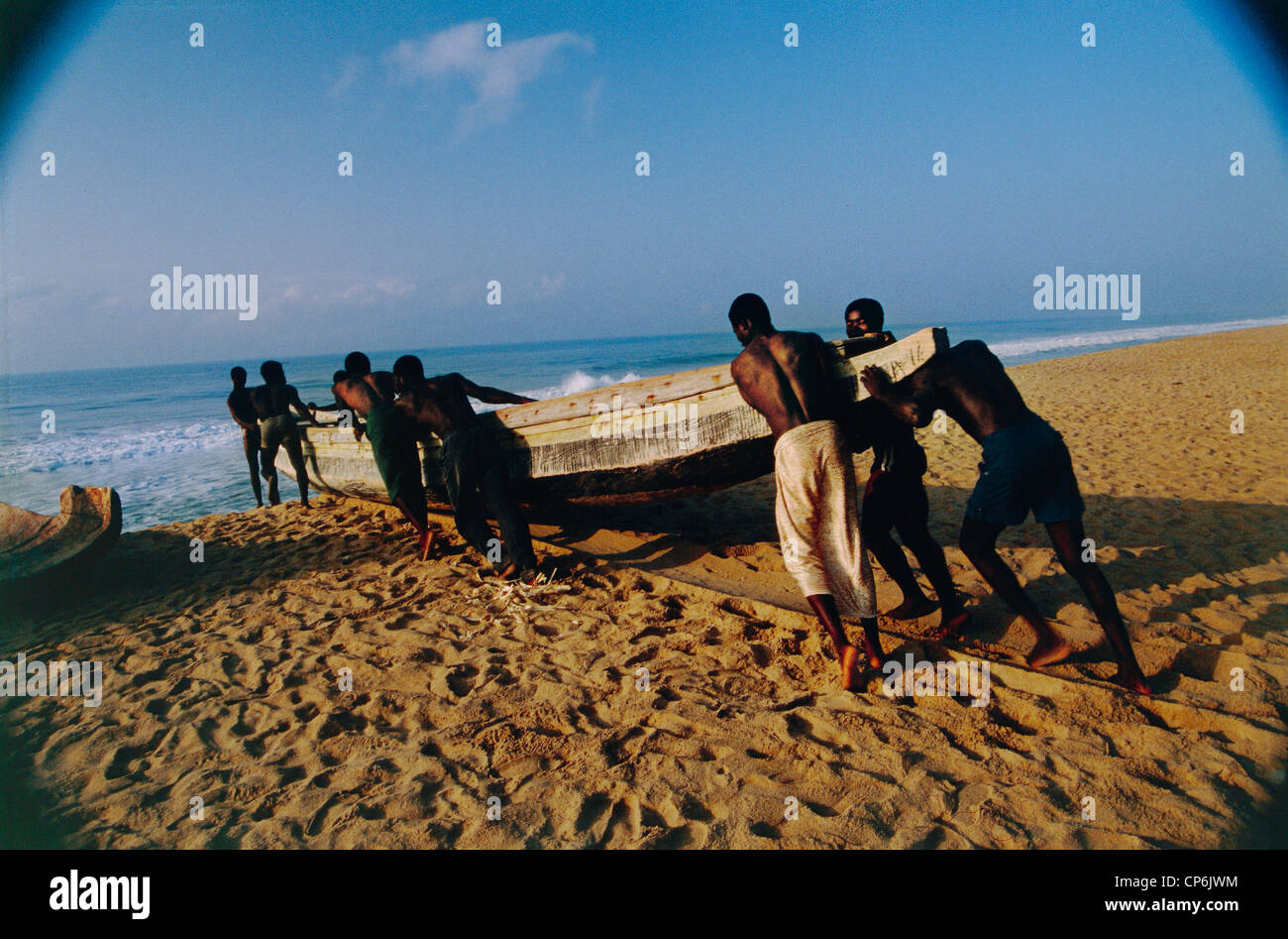 Togo - Maritime Region. A group of fishermen while pushing a boat in ...