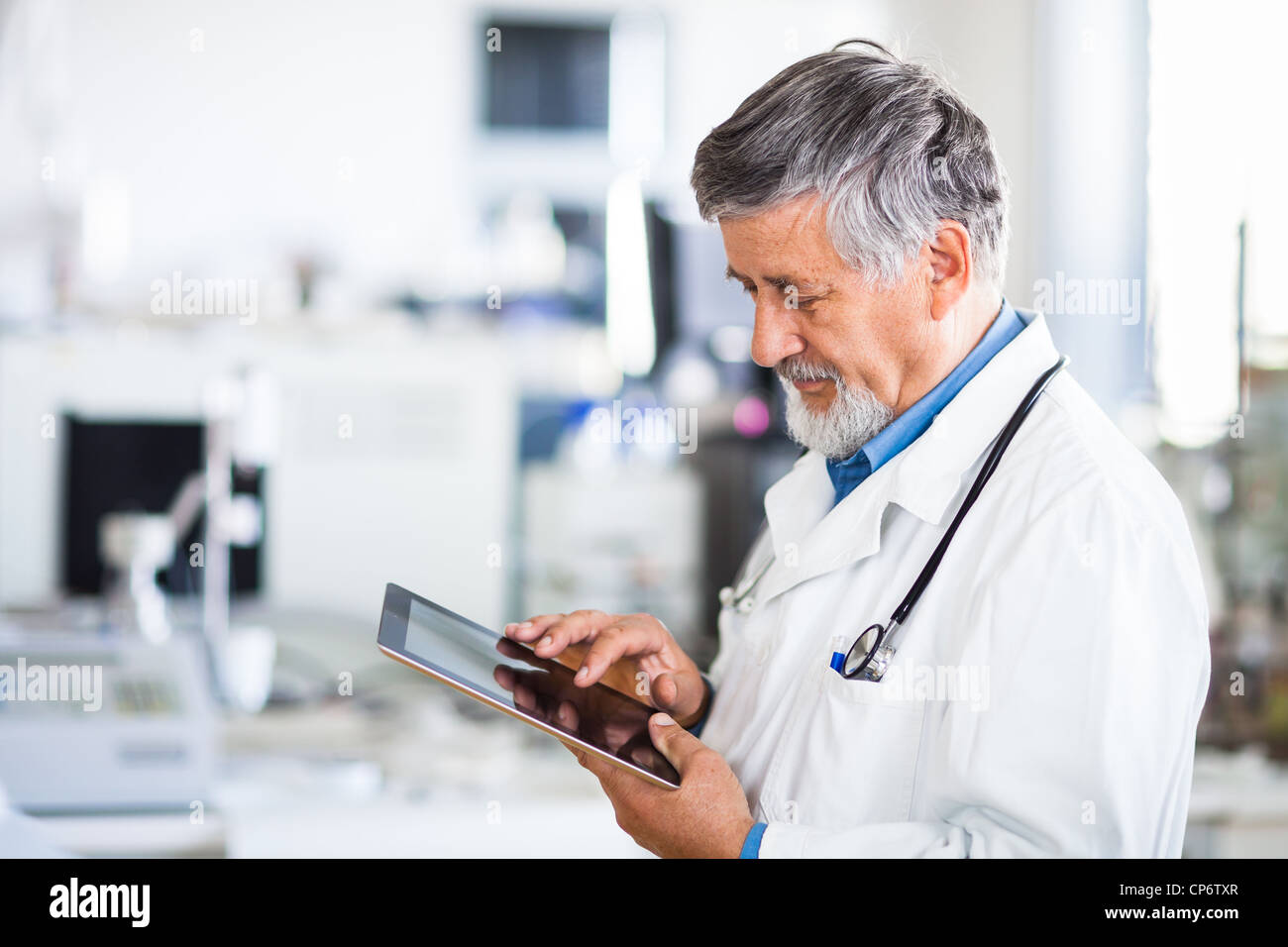 Senior doctor using his tablet computer at work (color toned image ...
