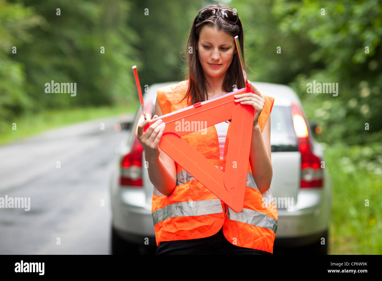 Young female driver wearing a high visibility vest, after her car has ...