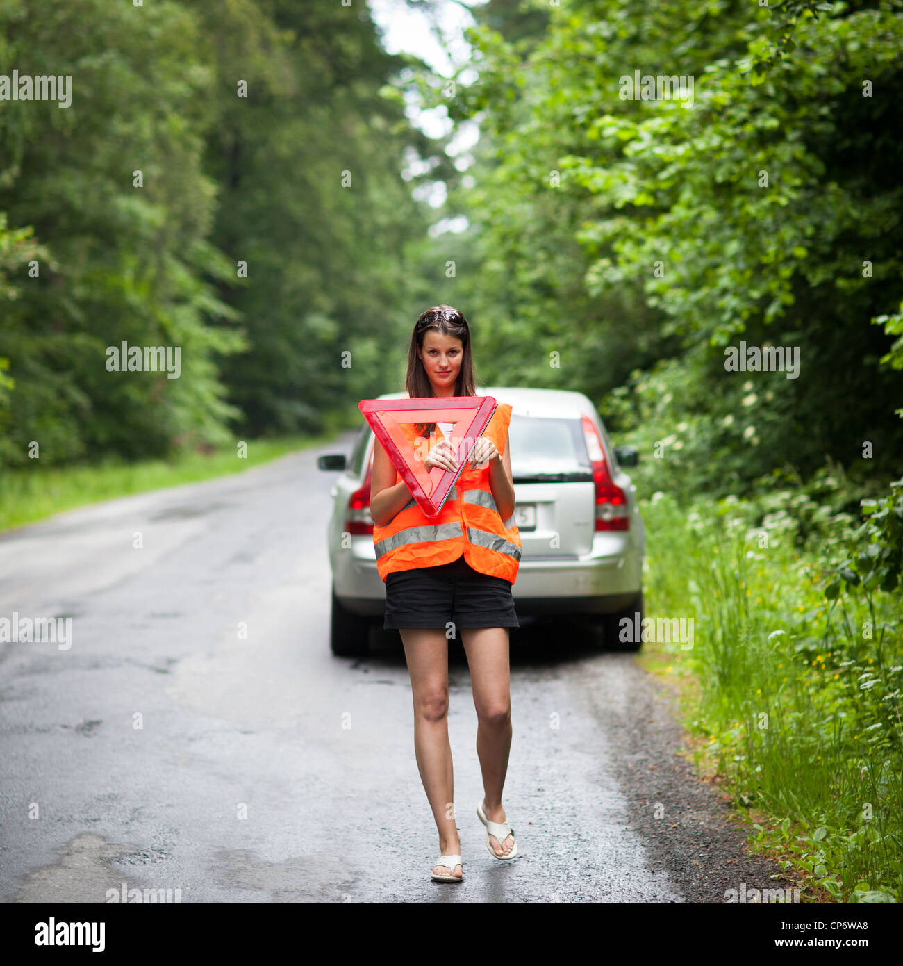 Young female driver wearing a high visibility vest, after her car has ...