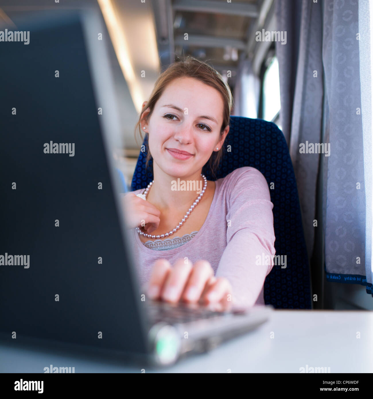 Young woman using her laptop computer while on the train (shallow DOF ...