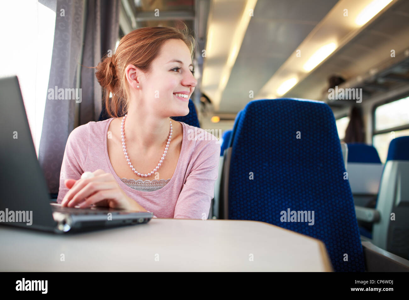 Young woman using her laptop computer while on the train (shallow DOF ...