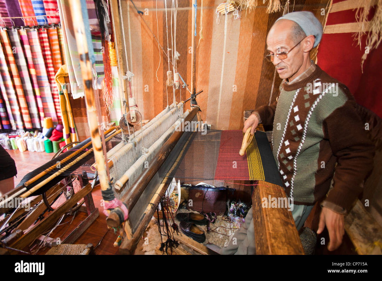 An old man working a loom to weave traditional Moroccan cloth in a souk ...