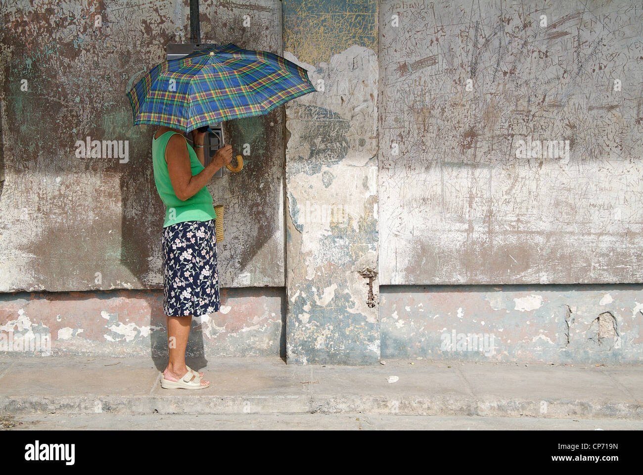 A woman with an umbrella using a public phone, Havana, Cuba Stock Photo ...