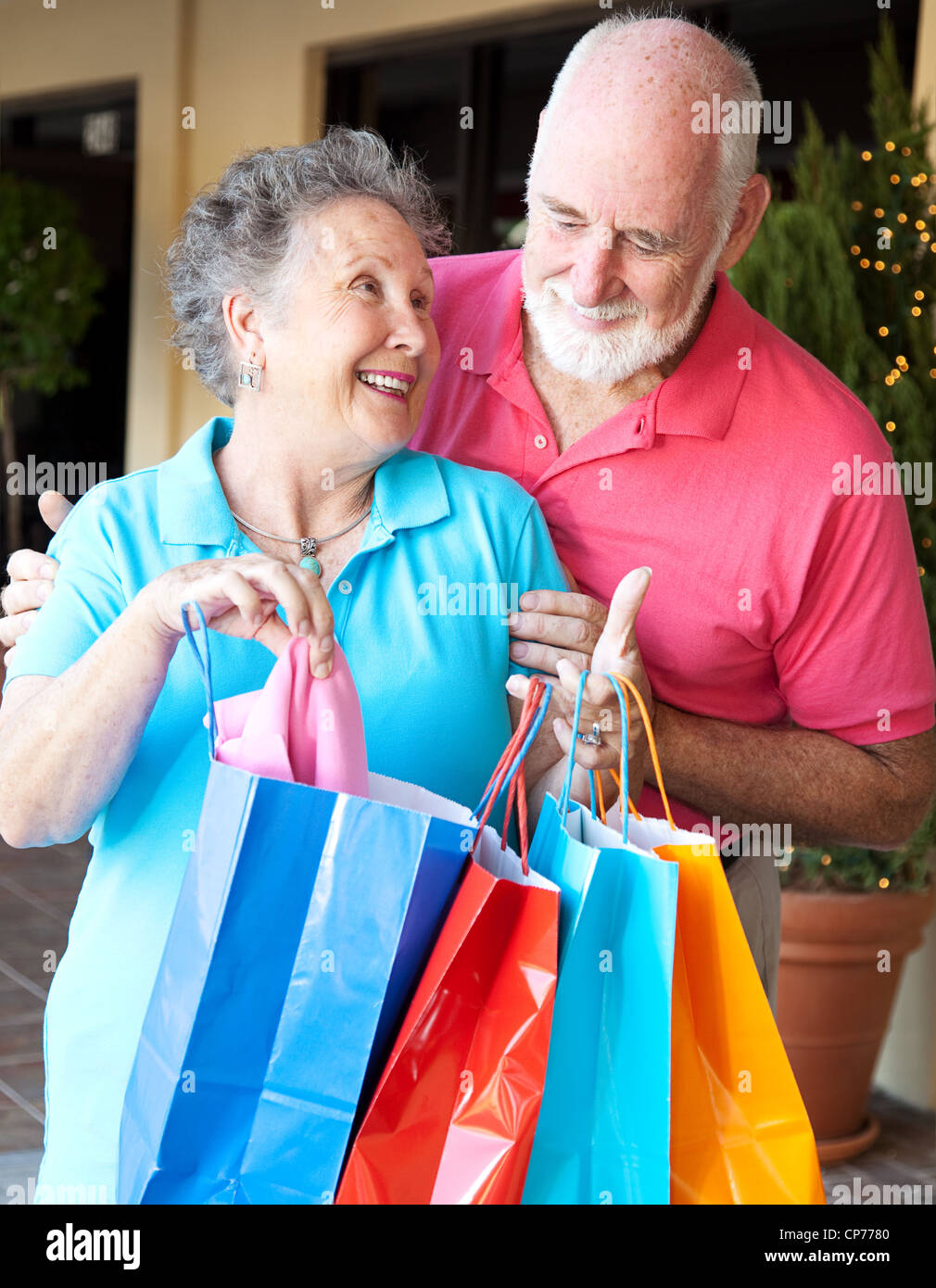 Senior man looks in the shopping bags to see what his wife has bought ...