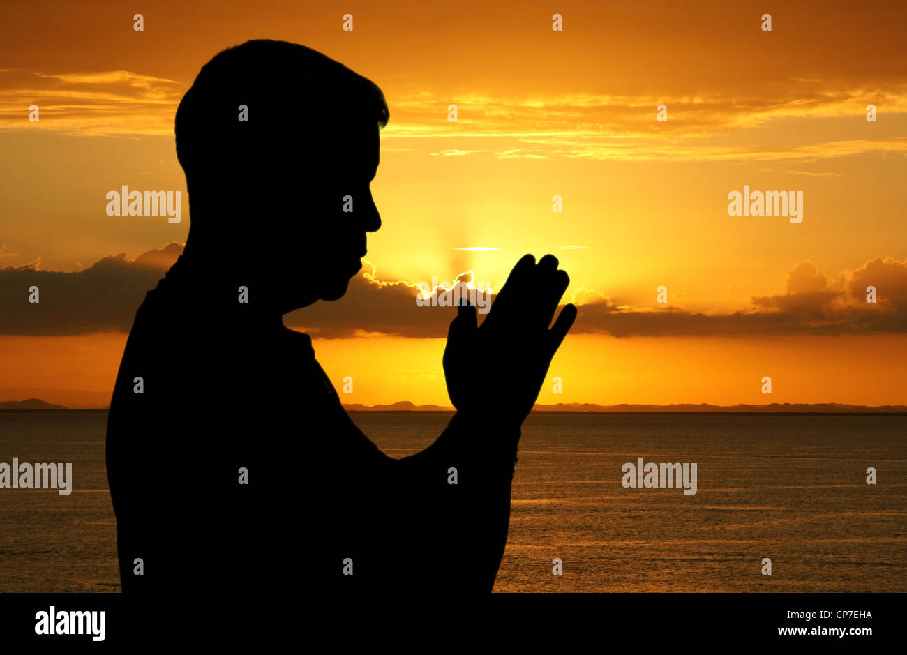 Man praying with his hands folded at sunset Stock Photo - Alamy