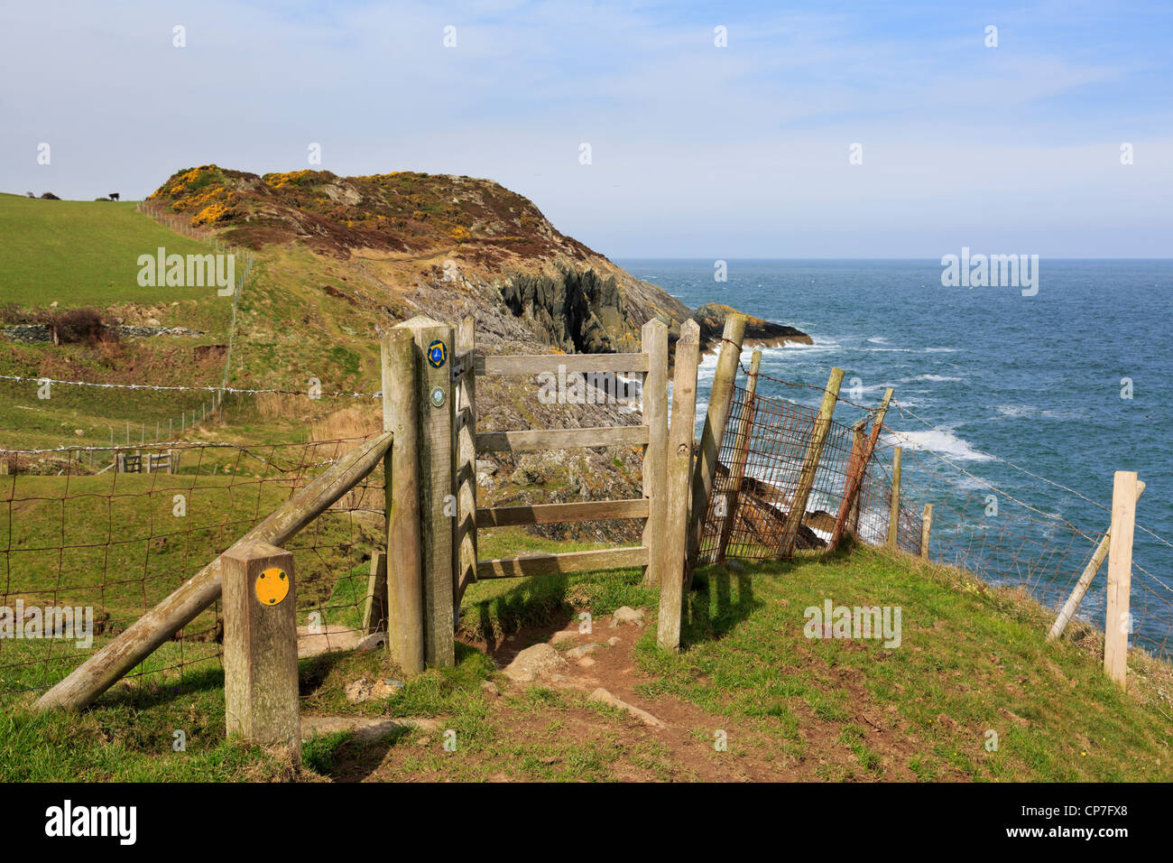 Kissing gate on the Isle of Anglesey Coastal Path with view along rocky ...