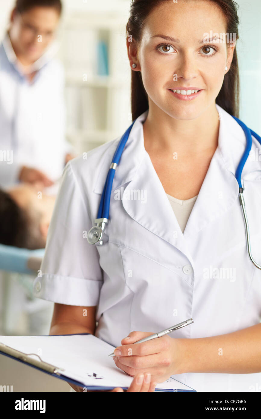 Pretty nurse in uniform ready to take notes holding a clipboard with a ...