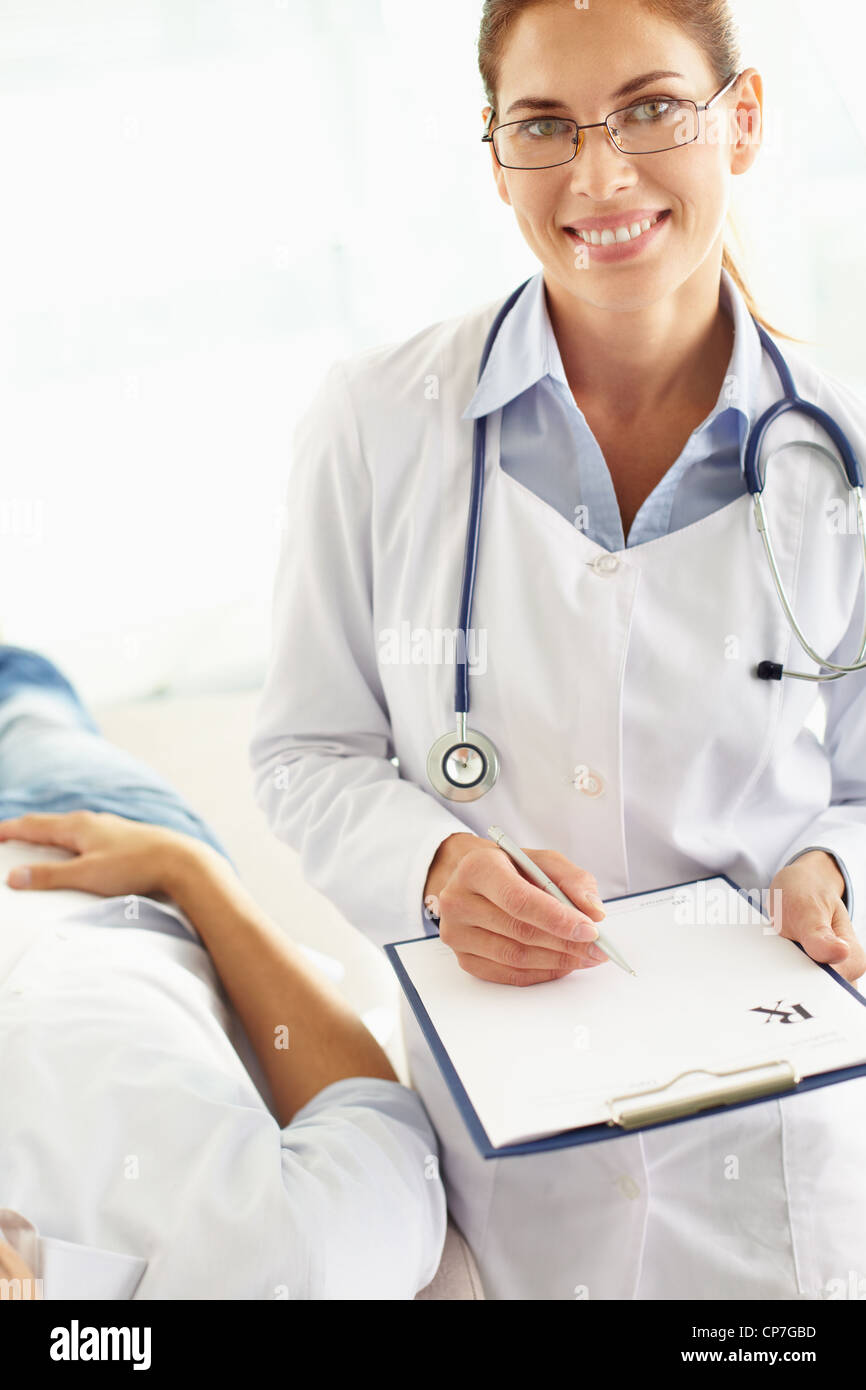 Portrait of a positive doctor holding the clipboard with an attached ...