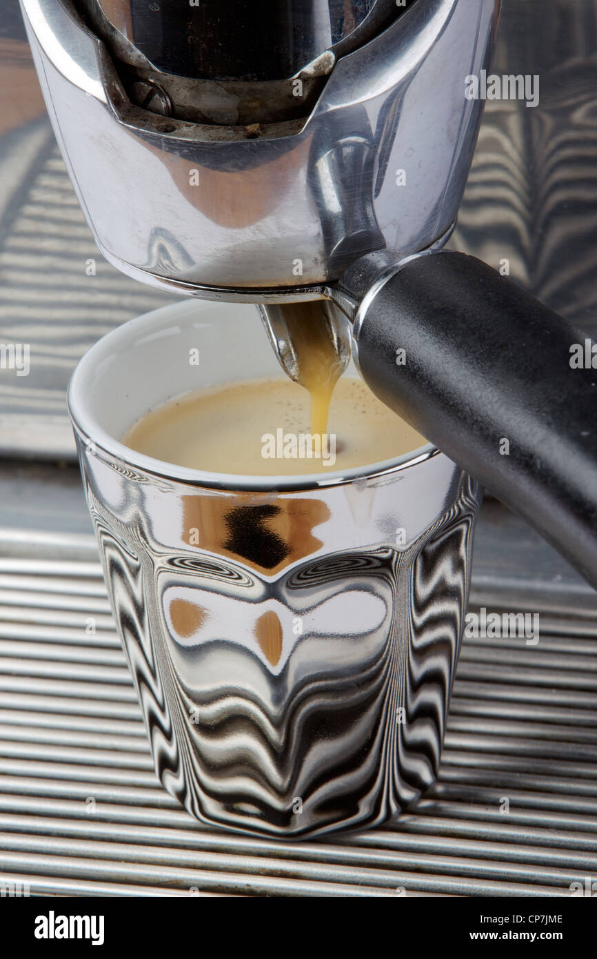 Chrome vintage espresso machine making a fresh cup of espresso into a ...