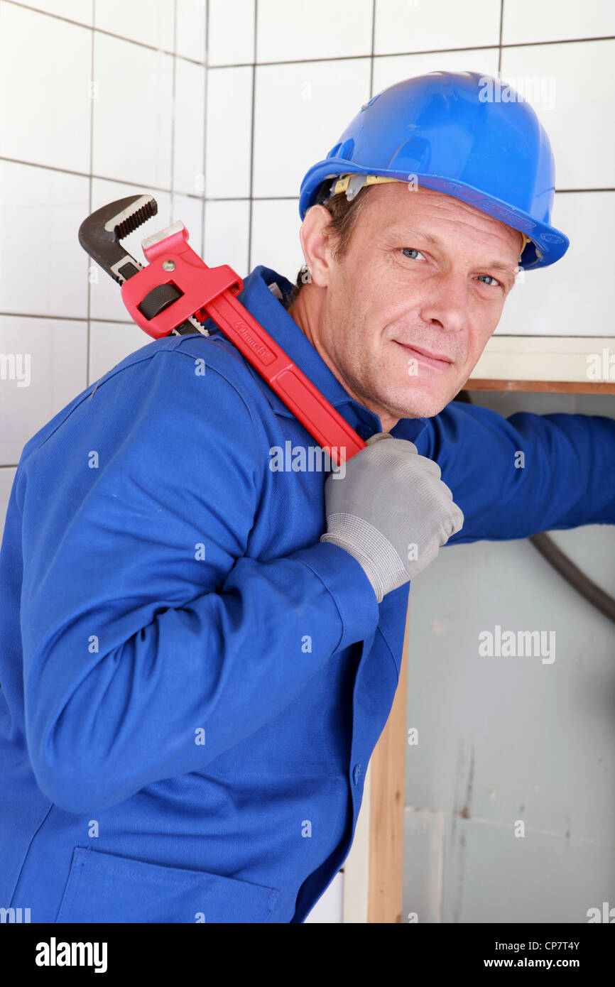 Plumber with a large red wrench held over his shoulder Stock Photo - Alamy