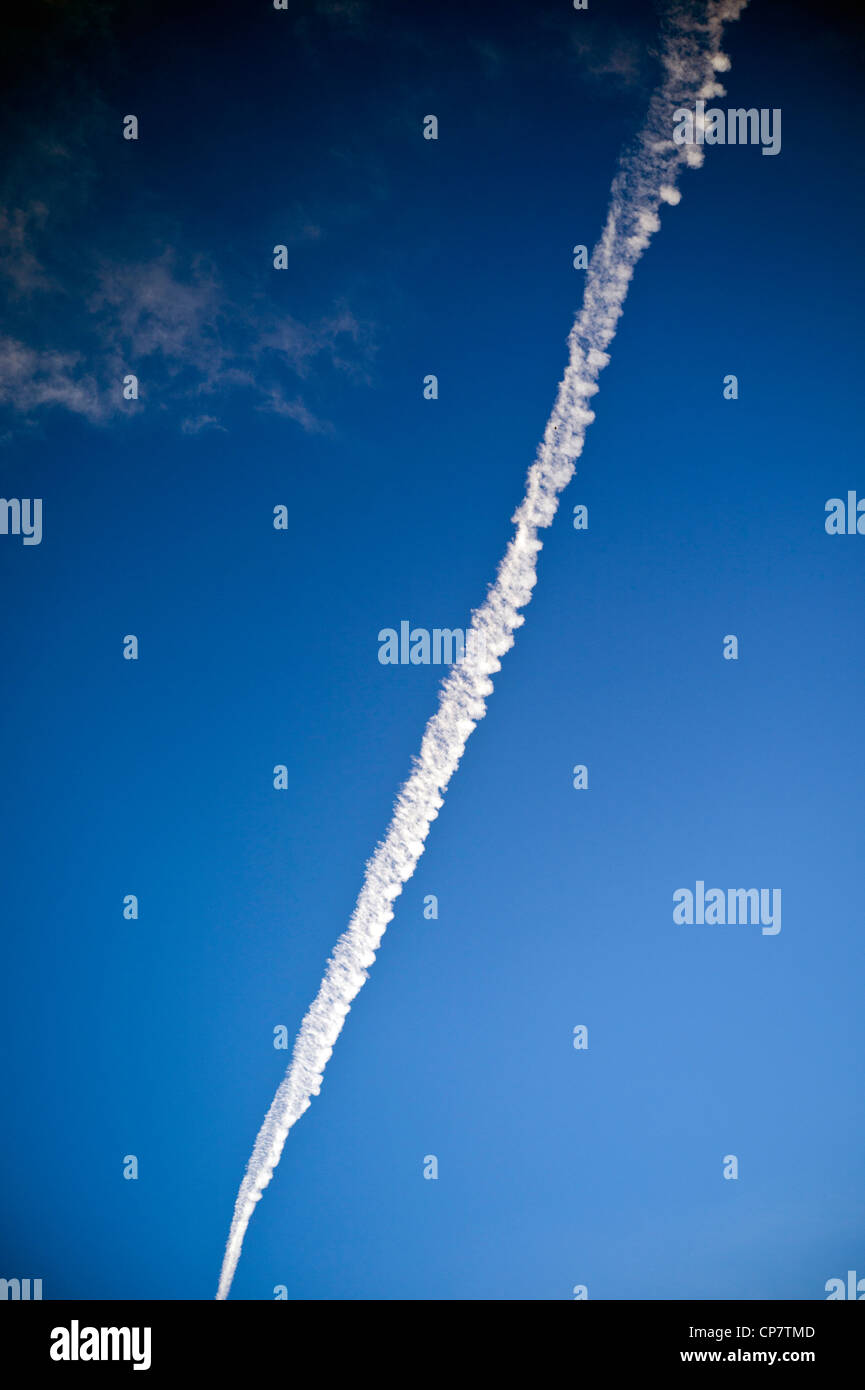 Commercial airline jet contrails across a clear dusk sunset blue sky ...