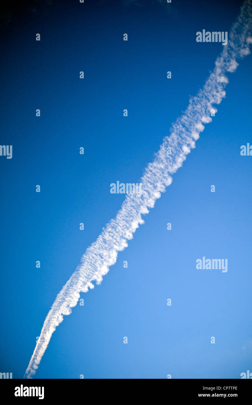 Commercial airline jet contrails across a clear dusk sunset blue sky ...