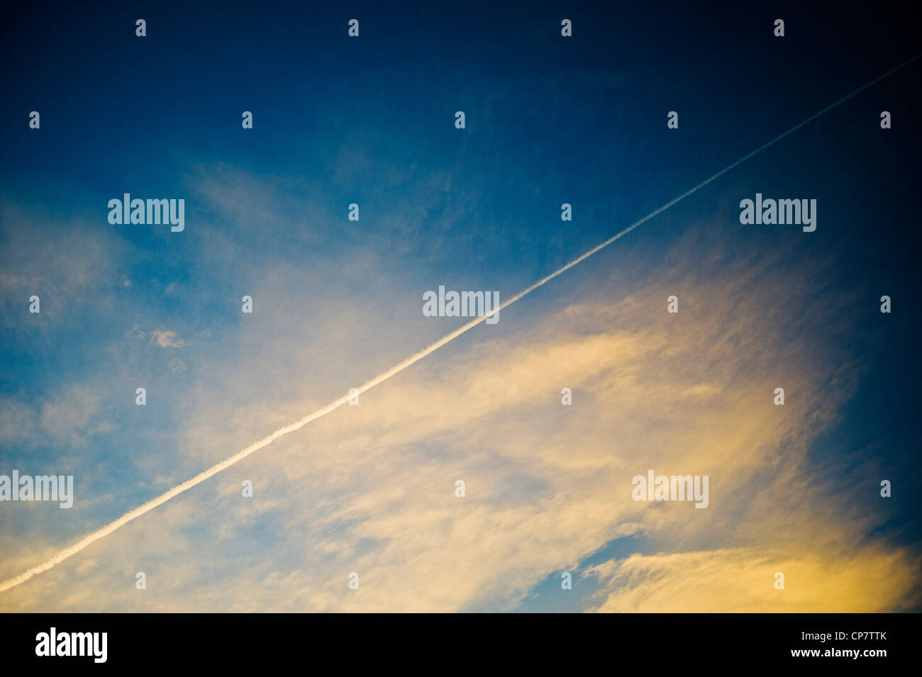 Commercial airline jet contrails across a clear dusk sunset blue sky ...