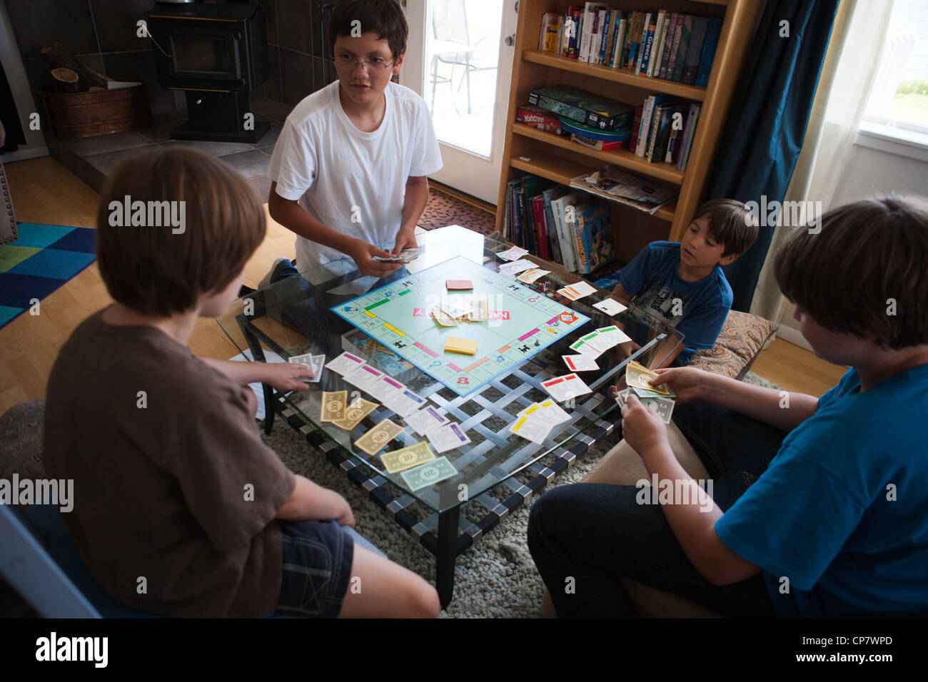 Four boys sitting on the floor playing Monopoly board game Stock Photo ...