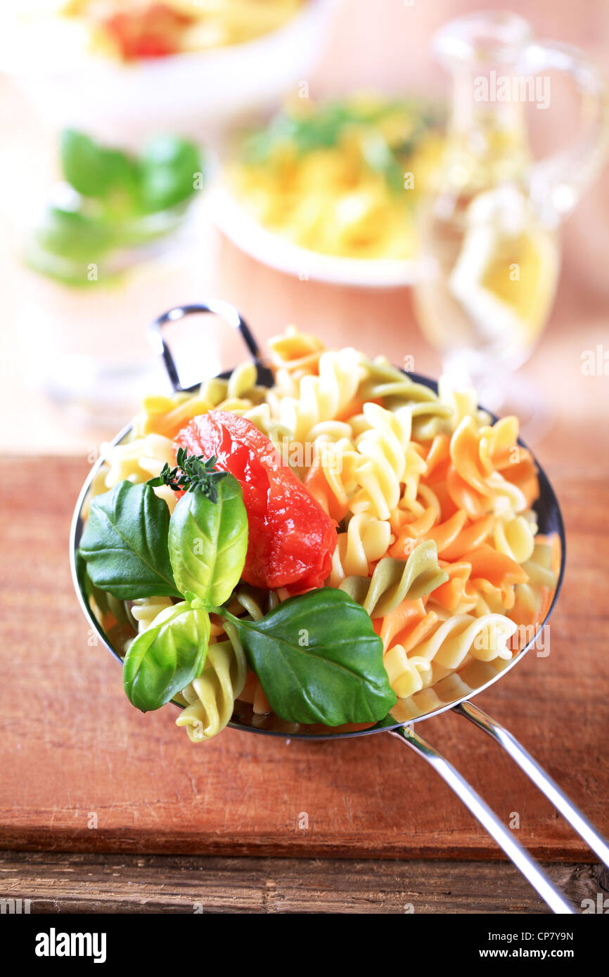 Tricolor corkscrew pasta in a metal sieve Stock Photo - Alamy