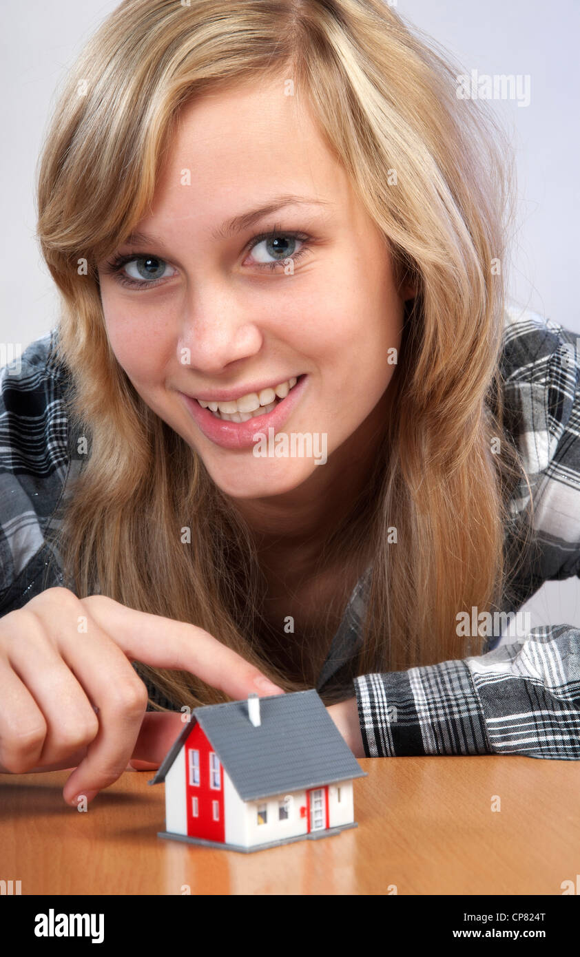 Young woman with model house as a symbol for the dream of a own house ...