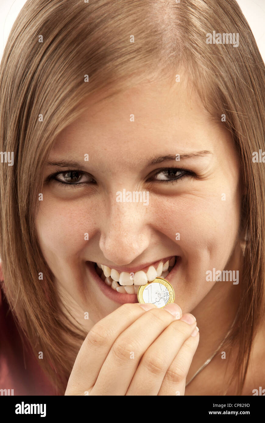 Young woman biting on a € coin Stock Photo - Alamy