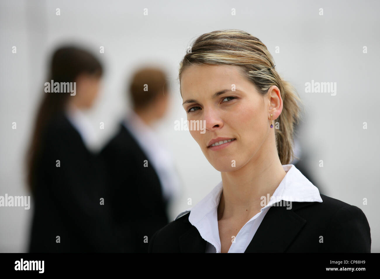 Blond woman stood with colleagues in background Stock Photo - Alamy