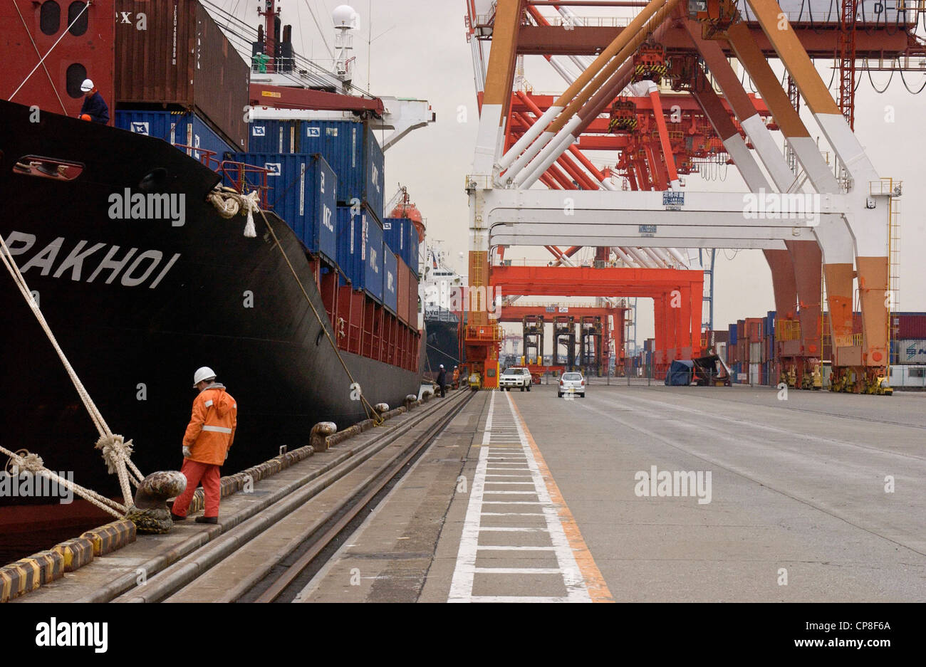 Workers look on as a container ship is loaded in the port of Yokohama ...