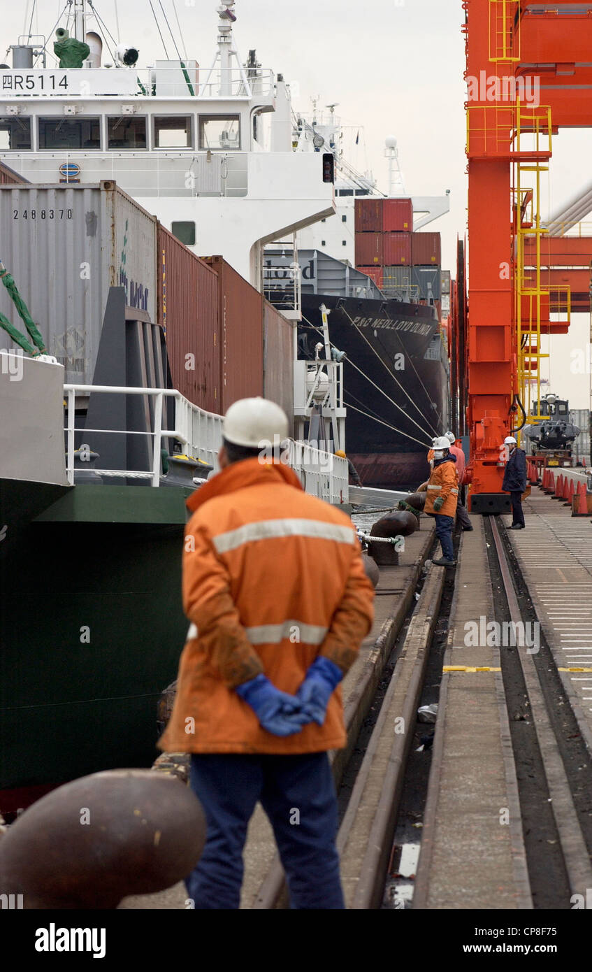 Workers look on as a container ship is loaded in the port of Yokohama ...