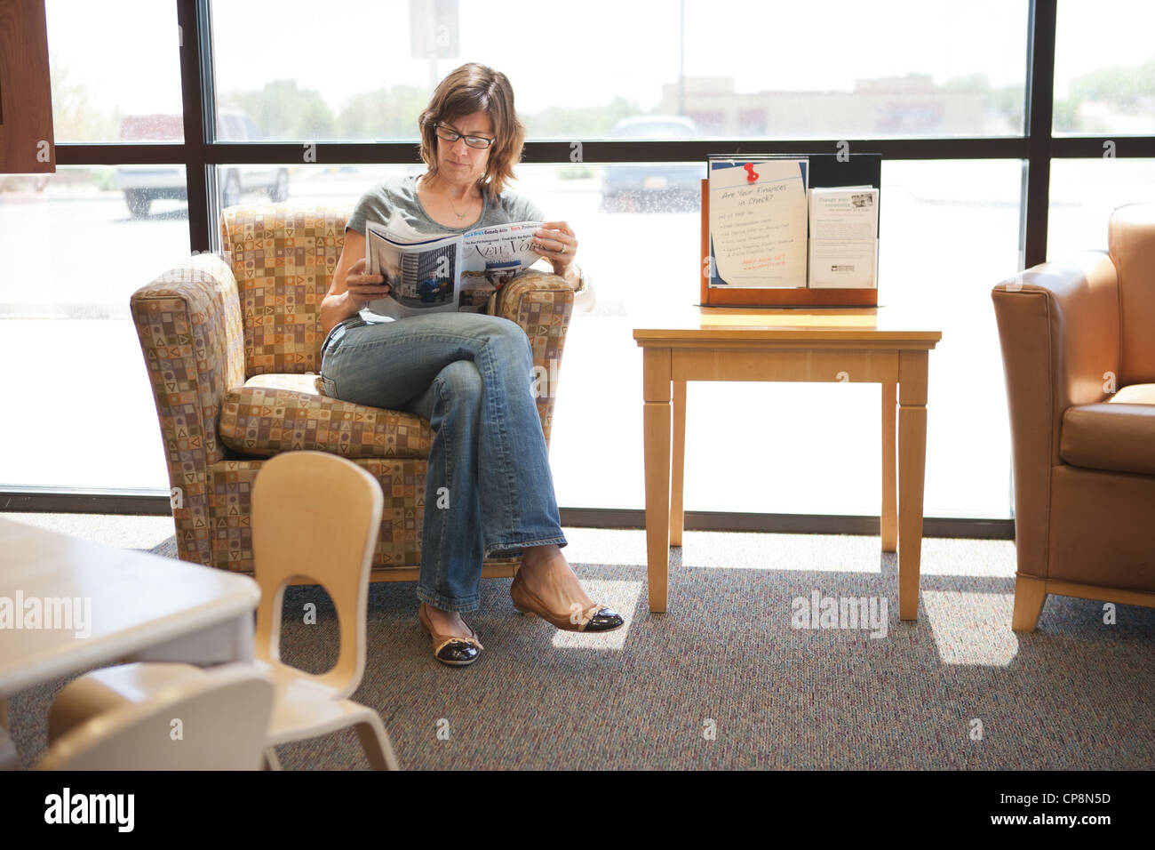 Woman reading a magazine in a waiting room Stock Photo - Alamy