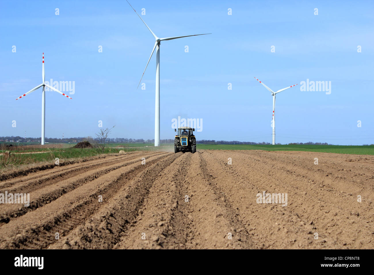 Tractor working in field over wind turbines farm Stock Photo - Alamy
