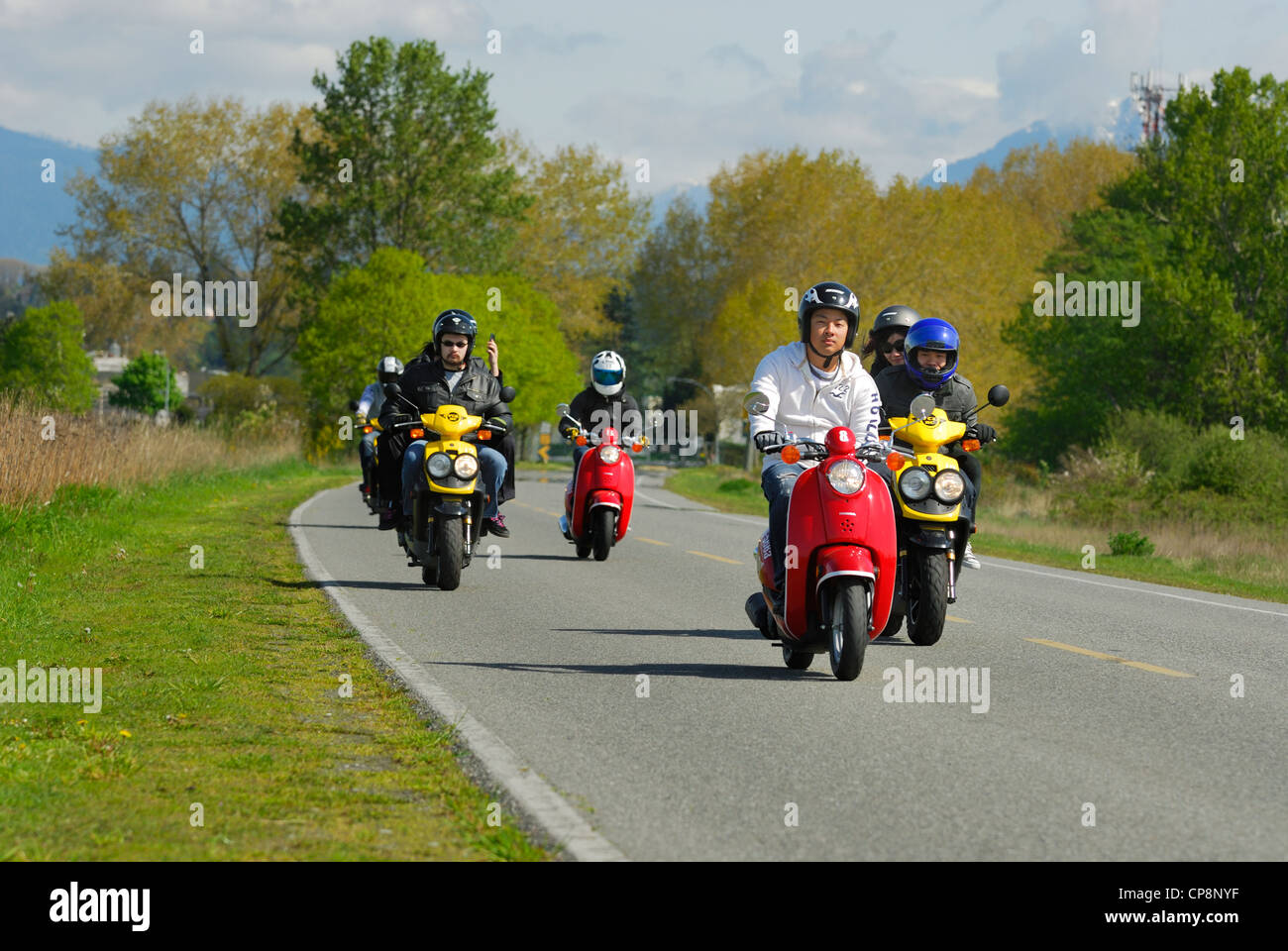 Group of scooters and motorcycles traveling down a roadway Stock Photo ...