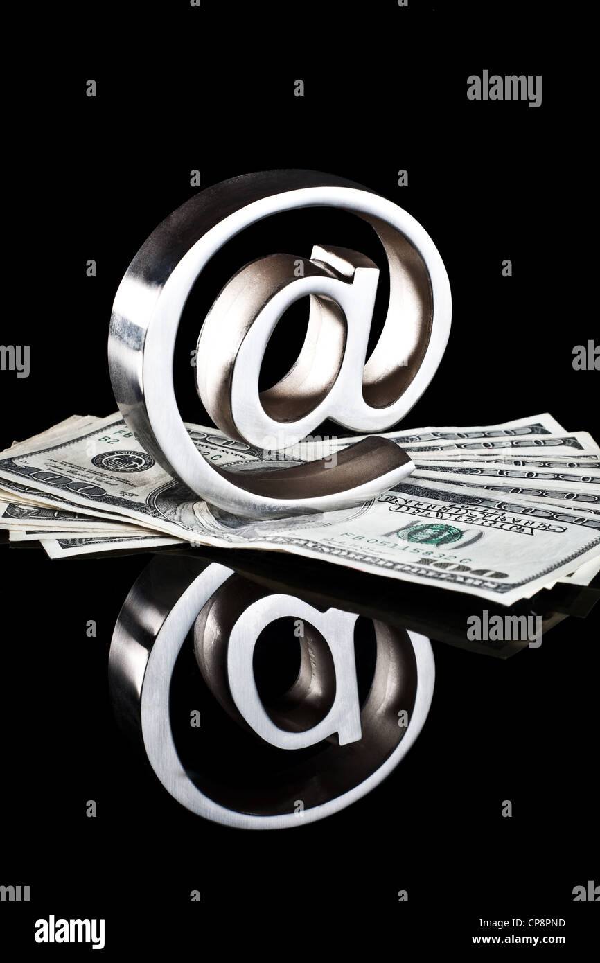 At symbol paperweight on a pile of 100 dollar bills Stock Photo - Alamy