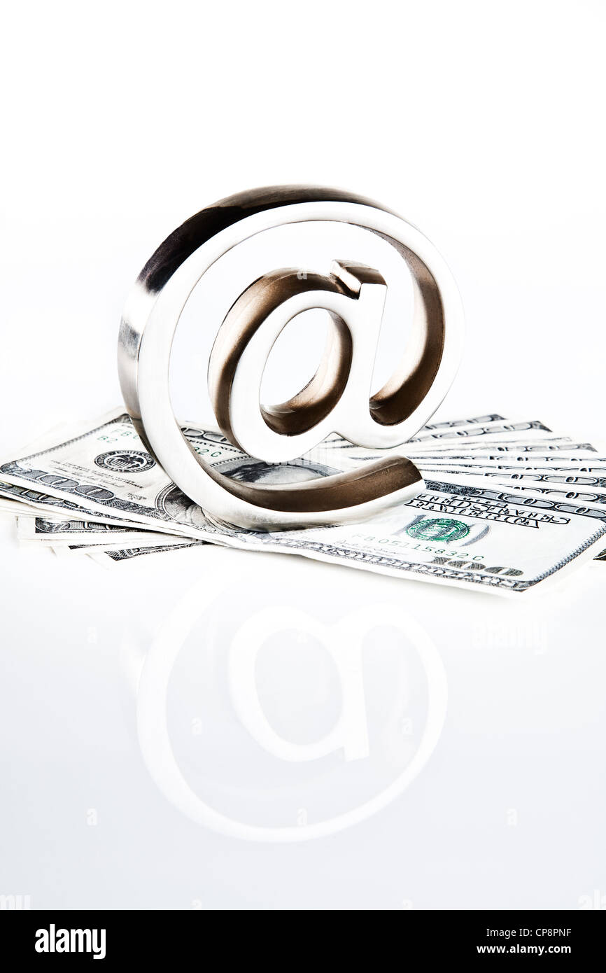 At symbol paperweight on a pile of 100 dollar bills Stock Photo - Alamy